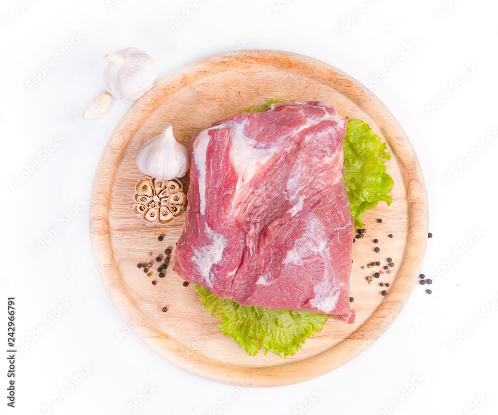 raw pork on a round board. pork tenderloin on lettuce leaves on a white ...