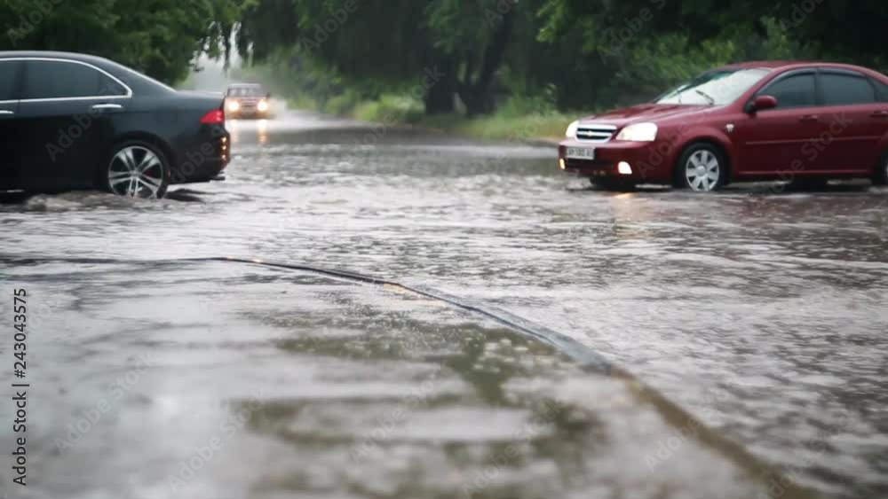 Car traffic on the flooded city street during heavy rain, heavy ...