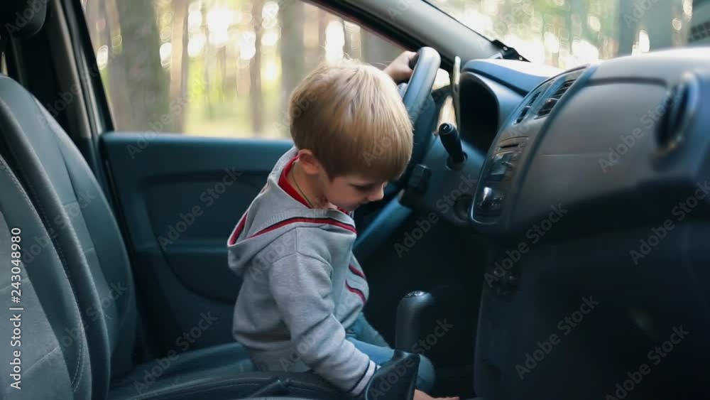 Cute child boy kid playing in the vehicle interior turns on the car ...