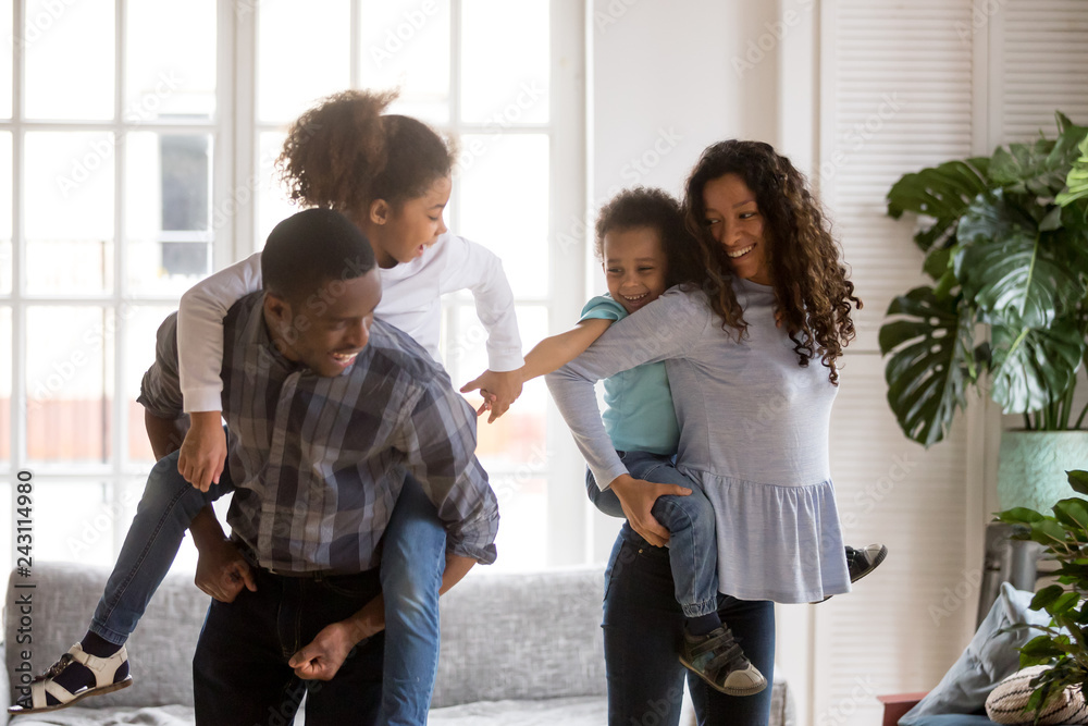 African american parents piggybacking son and daughter in living room ...