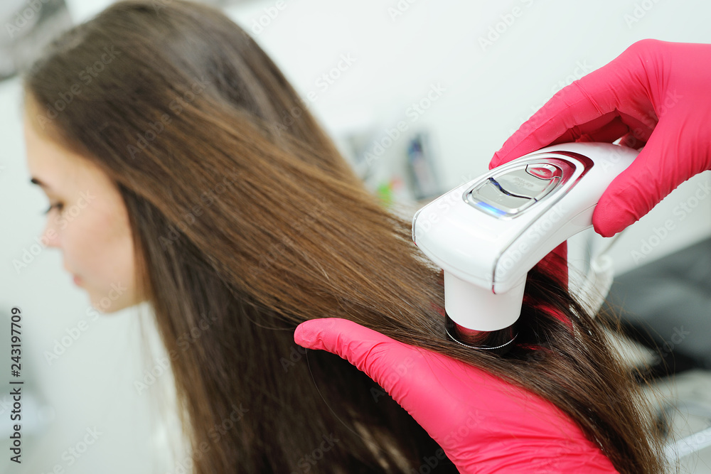 doctor dermatologist diagnoses the structure of the hair of a young ...