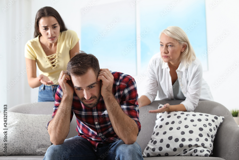 Young man having argument with wife and mother-in-law at home. Family ...