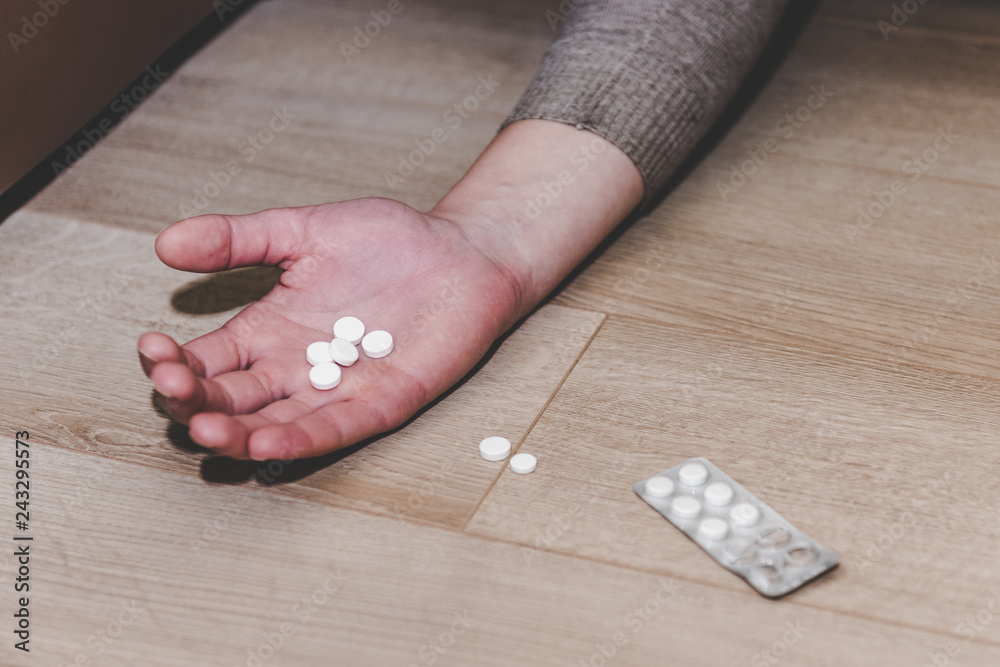 Drug abuse or poison pills concept. Hand on floor, pills. Suicide by ...