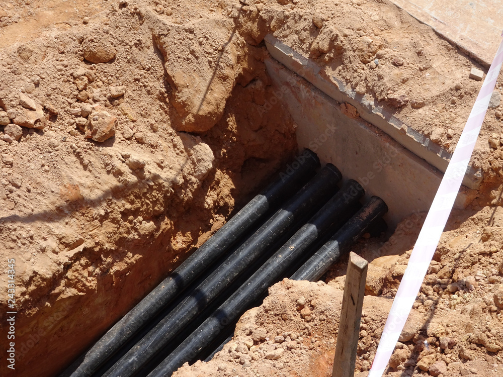 Underground utility and services pipe laid by workers in the trenches ...