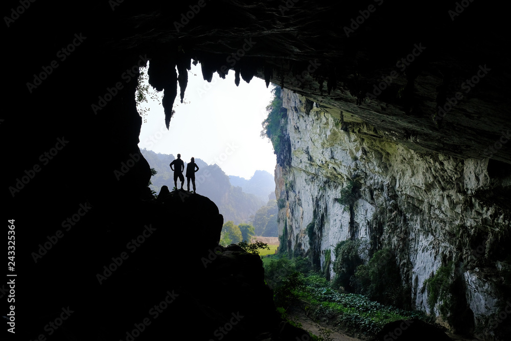 Silhouettes of two people standing in a rocky outcrop inside a giant ...