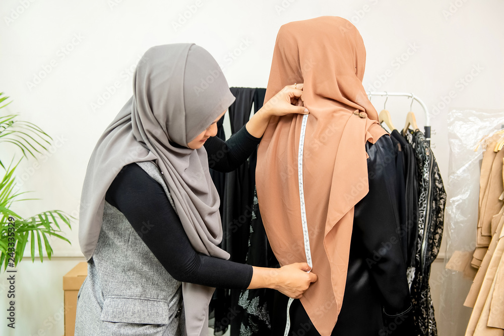 Female muslim designer measuring back of customer Stock Photo | Adobe Stock