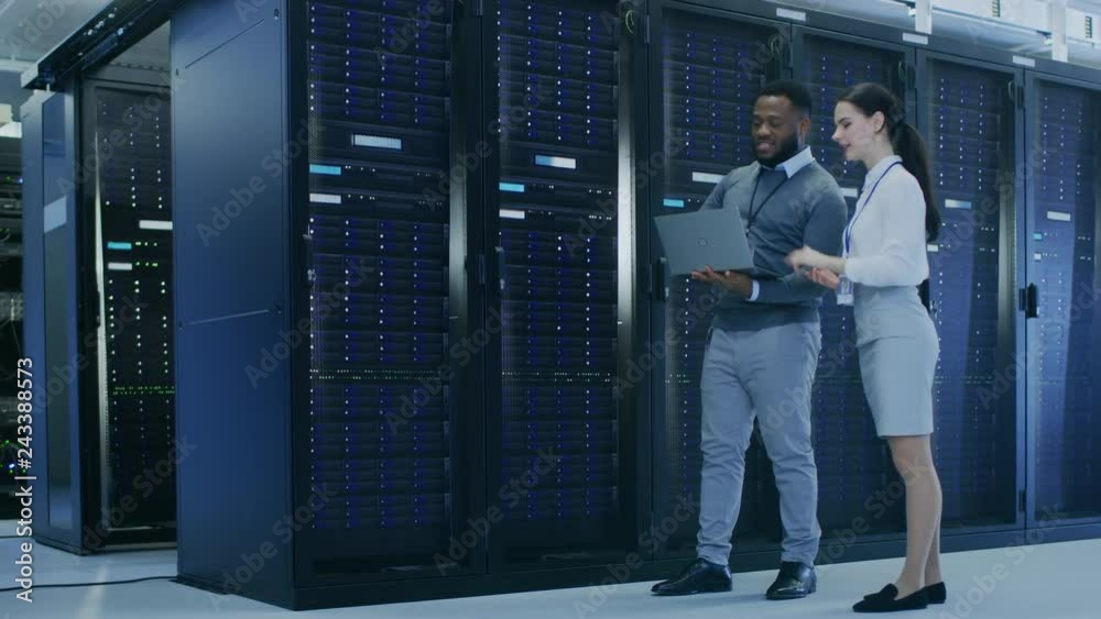 Black IT Technician with a Laptop Computer Gives a Tour to a Young ...