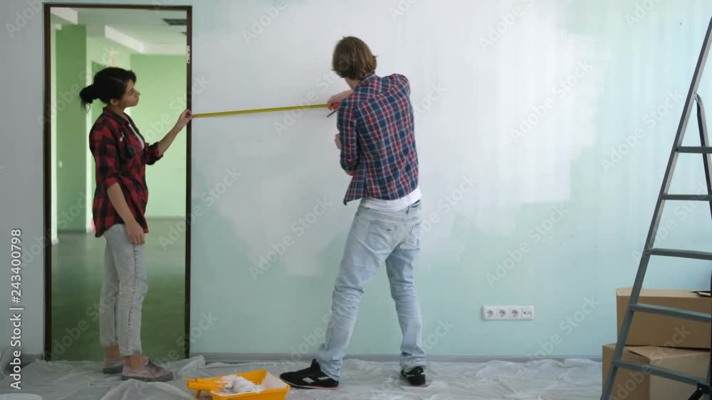Video Stock Rear view of positive multiracial couple measuring wall ...