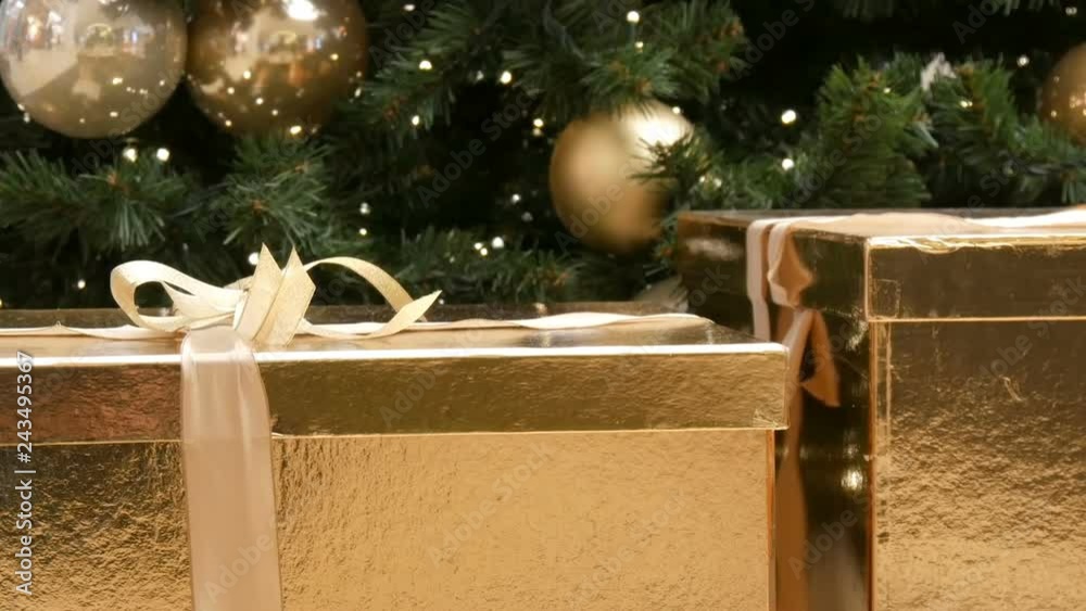 Large gift boxes, present of gold color under the Christmas tree in the ...