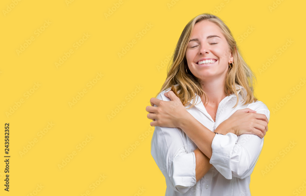 Beautiful young business woman over isolated background Hugging oneself ...