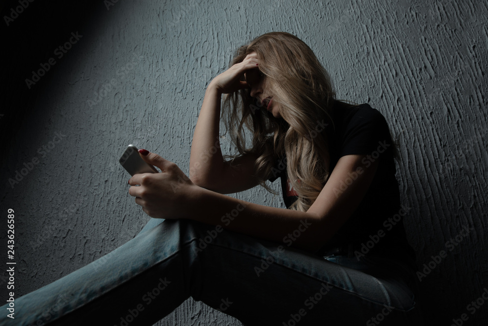 young scared and worried teenager girl holding mobile phone as internet ...