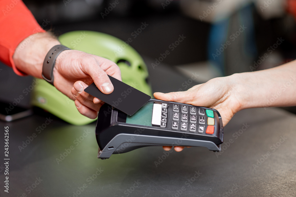Man making purchase with bank card and cash register at the counter of ...