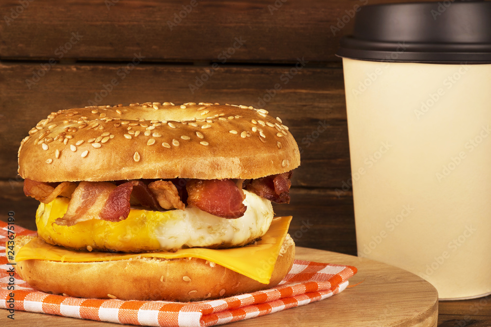 Sandwich breakfast with wooden plank in background. Bagel, egg, cheese ...