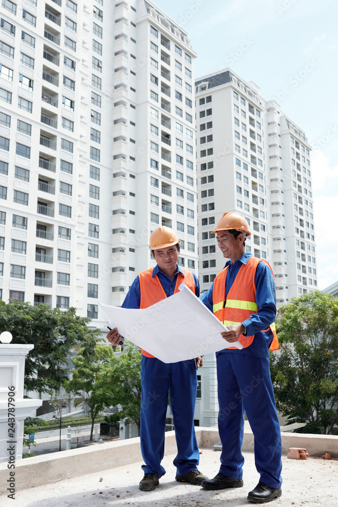 Smiling Vietnamese civil engineers discussing construction plan Stock ...