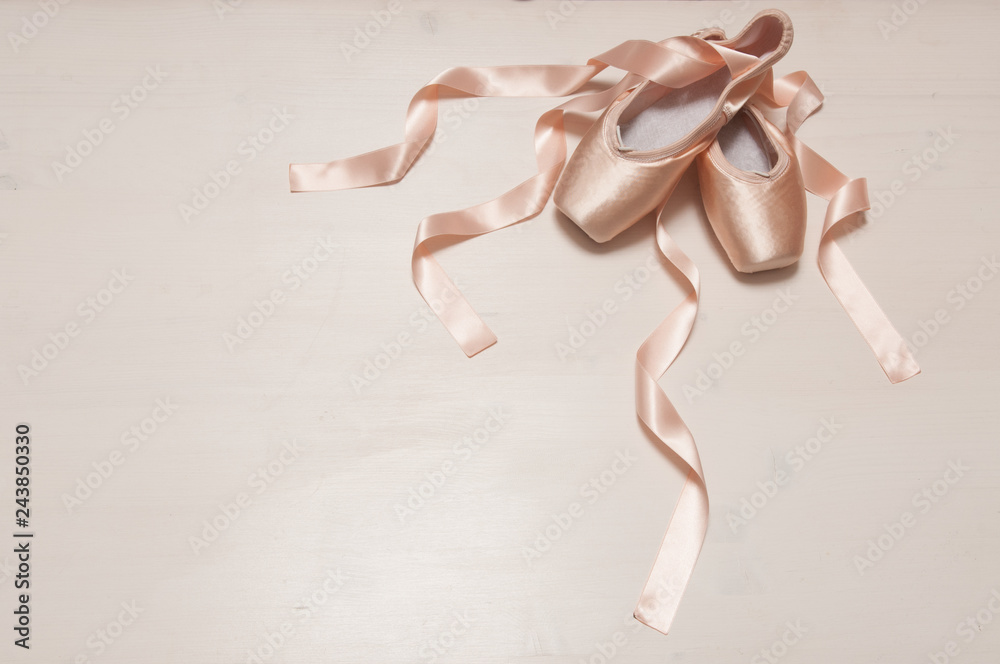 Pair of two satin ballet shoes with long ribbons lying on a white ...