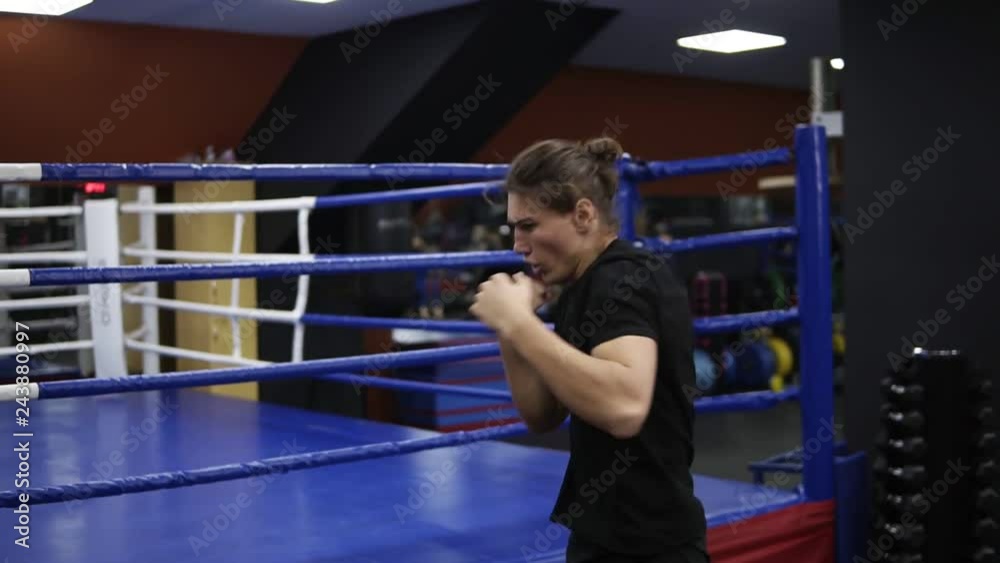 Angry man training near boxing ring in modern gym. Fighting the shadow ...