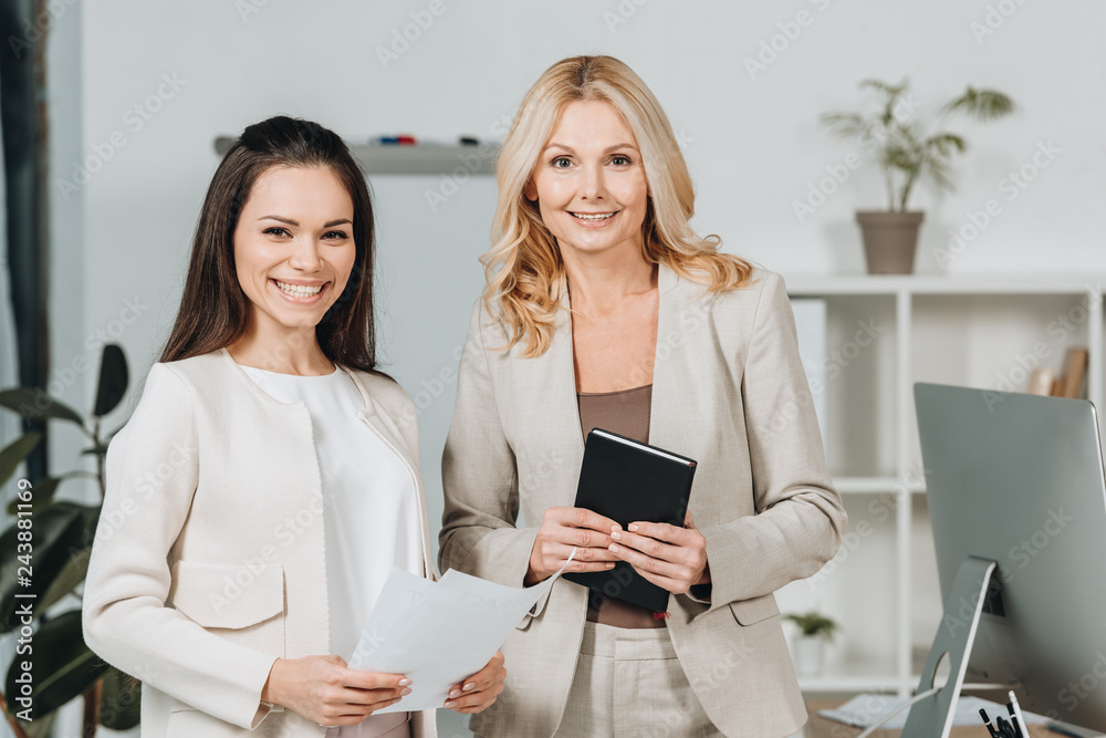 beautiful professional businesswomen with papers and notebook standing ...