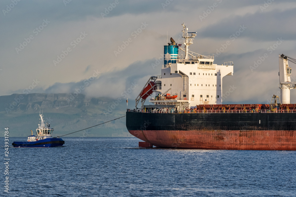Tugboat pulling a Cargo Ship Stock Photo | Adobe Stock
