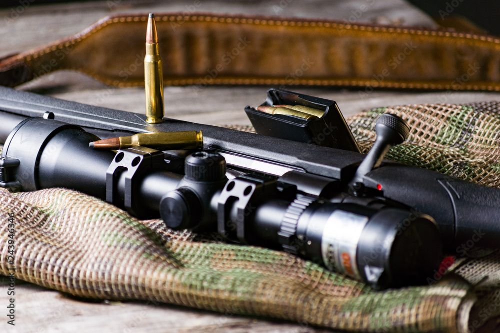 The Ammo with black bolt action rifle and scope on the multicam ...