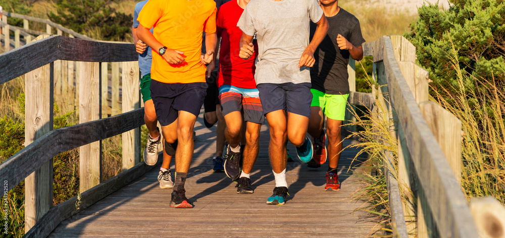 Group of teenagers running on a boardwalk in sunshine Stock Photo ...