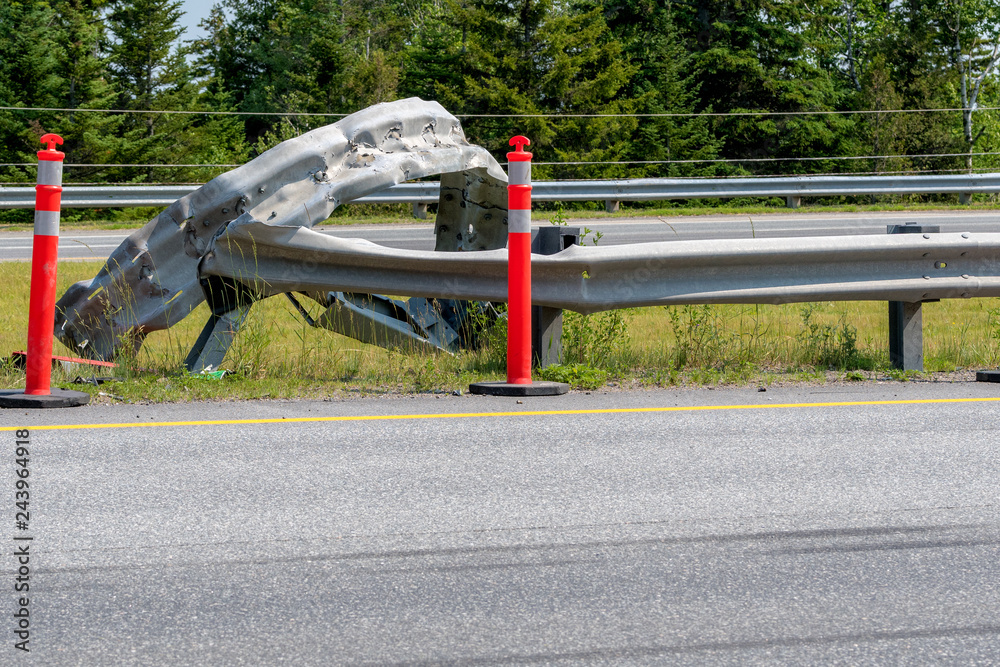 A bent and twisted guard rail at the side of a highway.It appears to ...