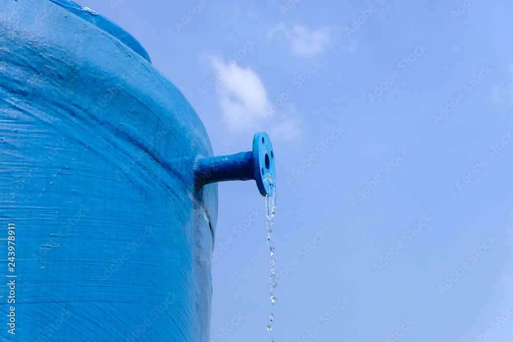 Water flows from blue water tank on sky backgrounds. Stock Photo ...