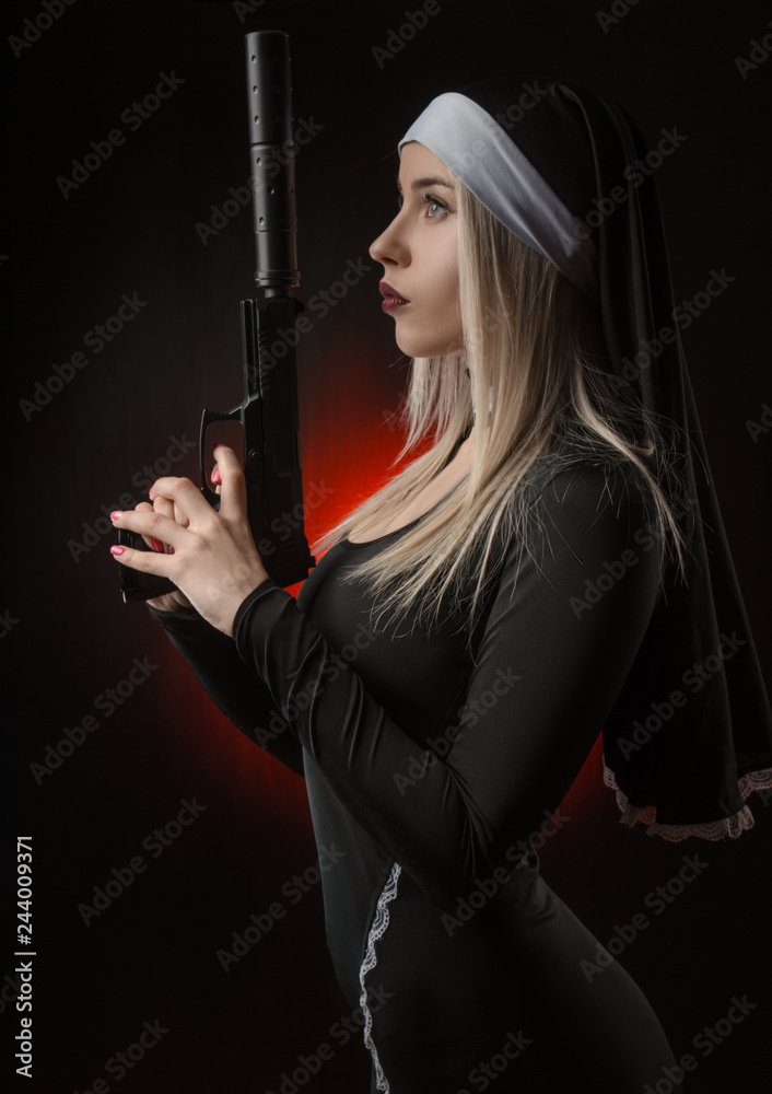 girl on a black background in a nun dress posing with a gun, aiming ...