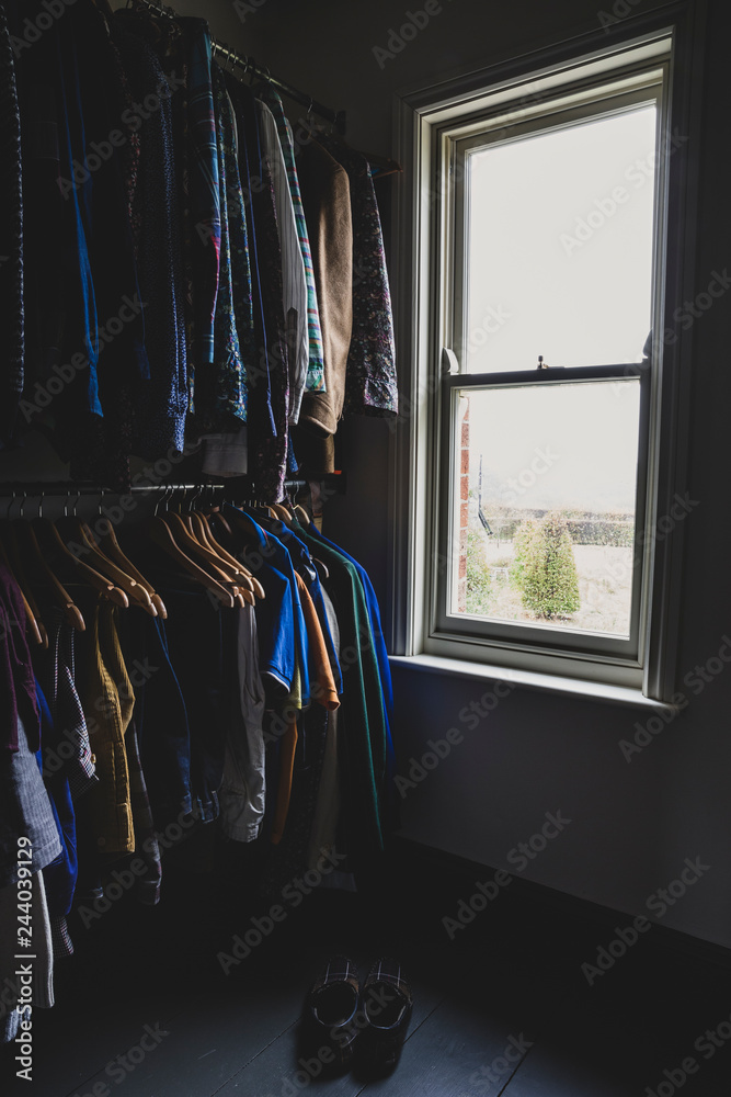 Interior view of walk-in wardrobe with sash window and clothing on ...