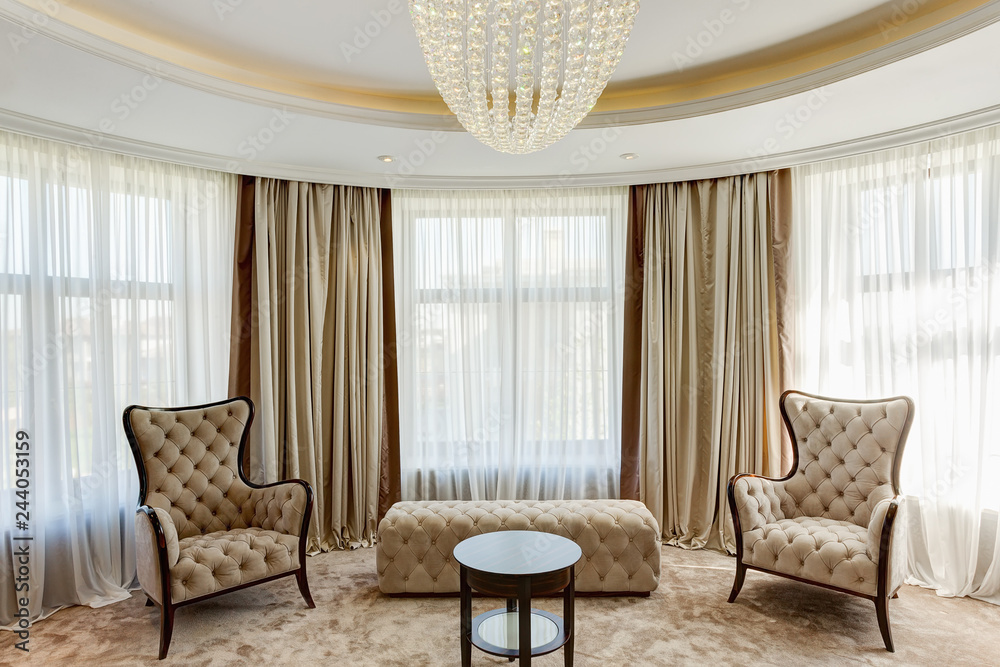 Living room with big windows in beige and brown colors. Classic ...