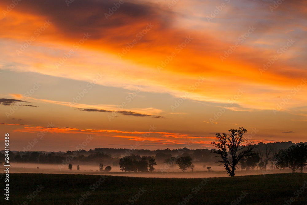 A bright orange sunset over farmland and ground fog. Stock Photo ...