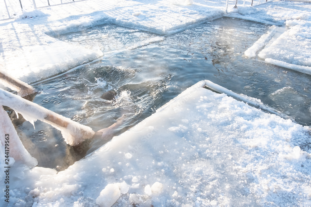 Winter tradition. The man plunged headlong into cold water into a hole ...