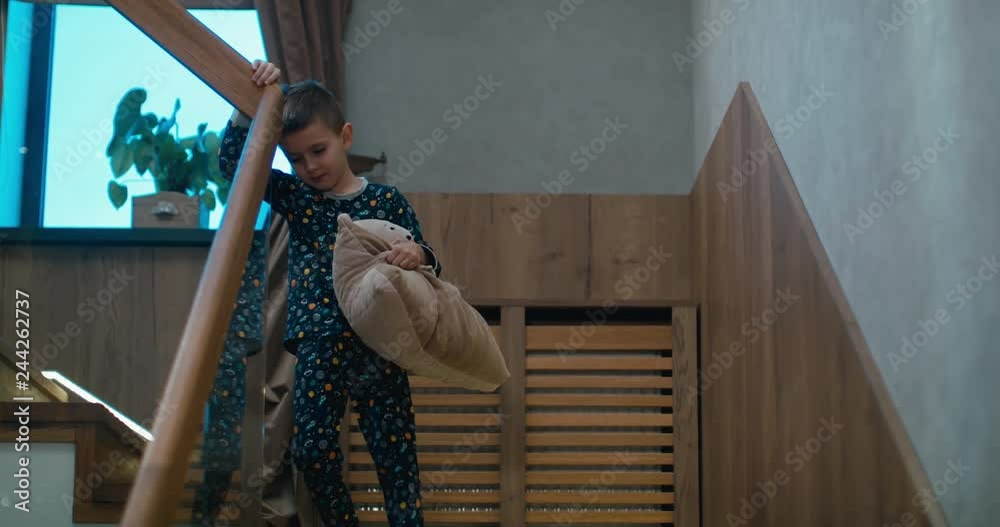 Cute little sleepy kid boy walking down stairs in the morning, with ...