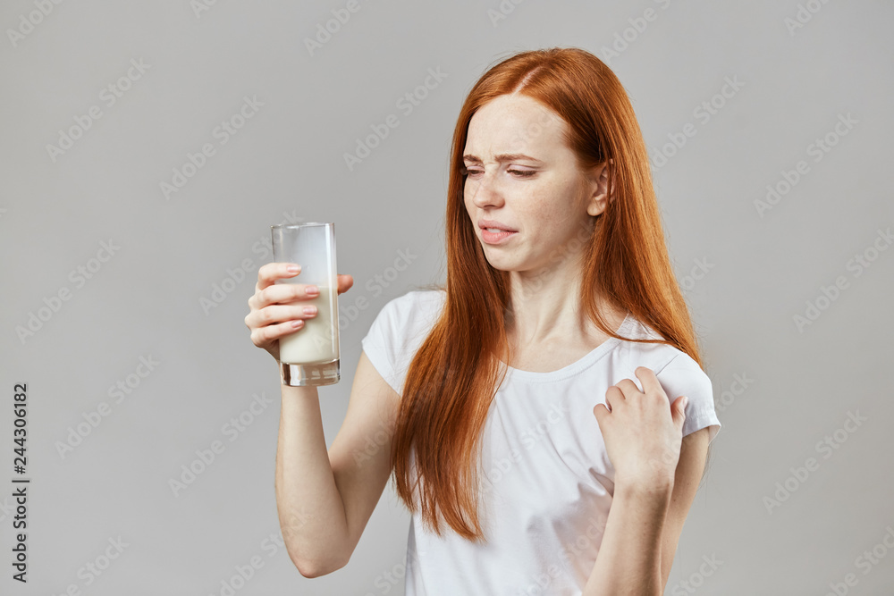 Little unhappy girl with a glass of milk isolated on white background ...