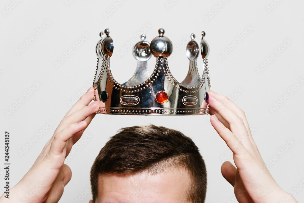 Man hands holding crown over his head, on light gray background, in ...