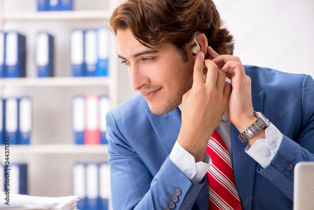 Deaf employee using hearing aid in office Stock Photo | Adobe Stock