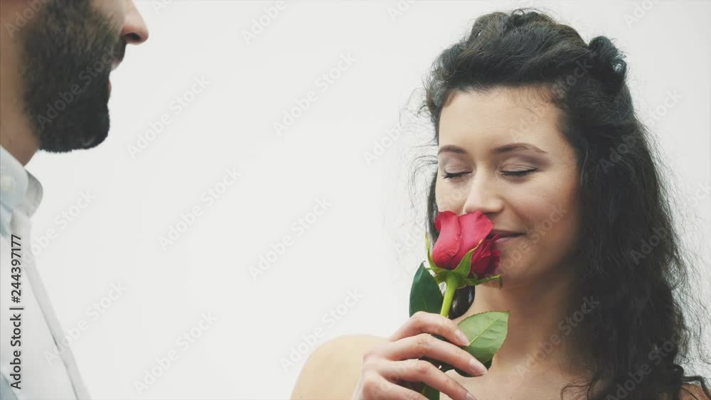 Beautiful elegant guy in a classic shirt with red roses in his hands ...