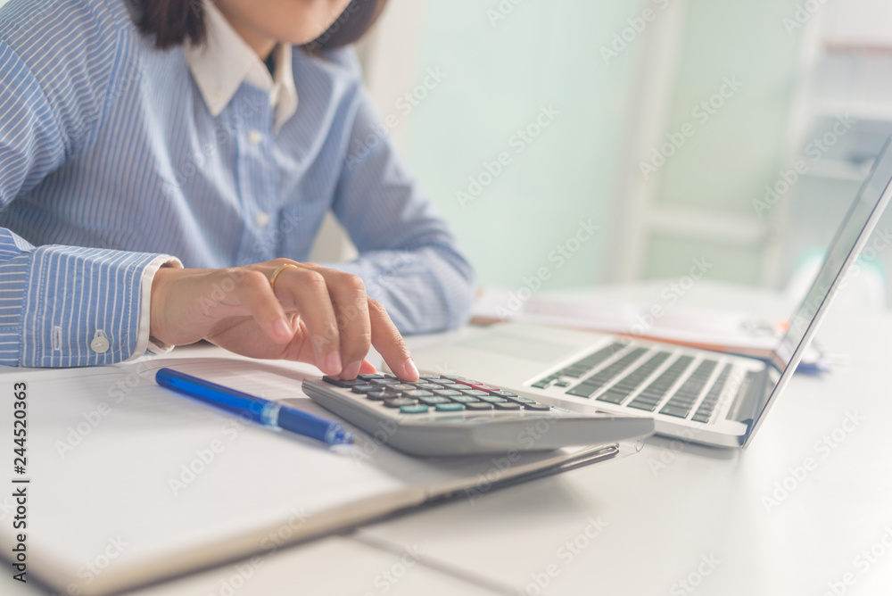 Young Asian woman using calculator to count number of sales in modern ...