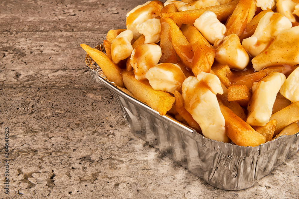 Partial close up on a poutine in a takeout container. Cooked with ...