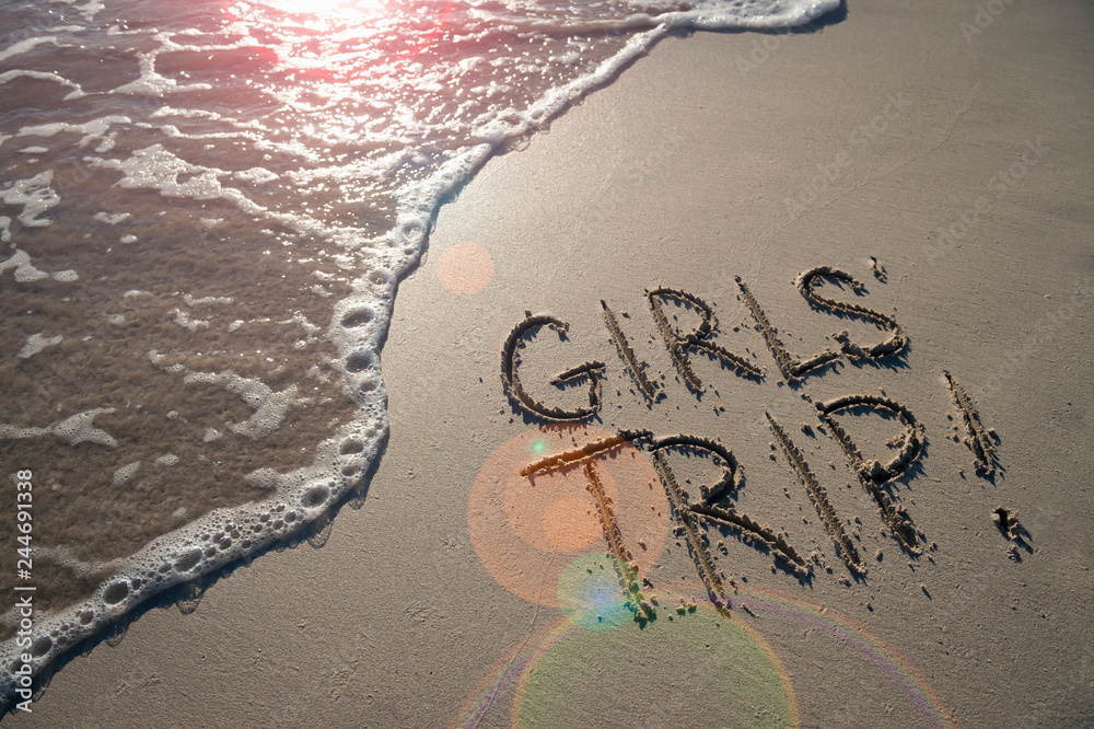 Girls Trip message handwritten on the smooth sand shore of a beach with ...