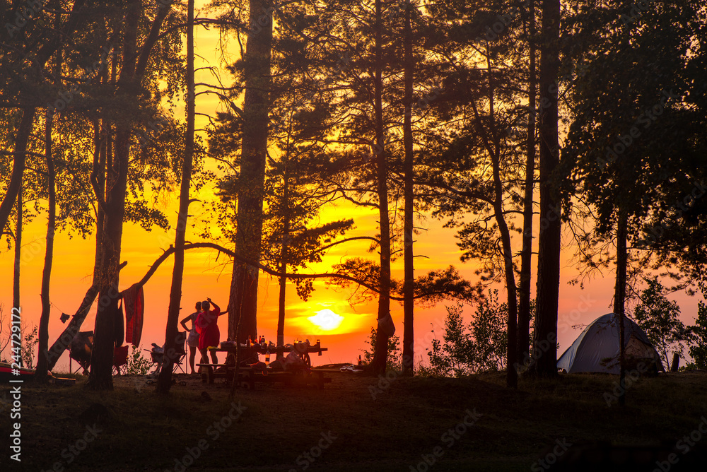 Camping on the beach during the sunset with silhouettes of young people ...