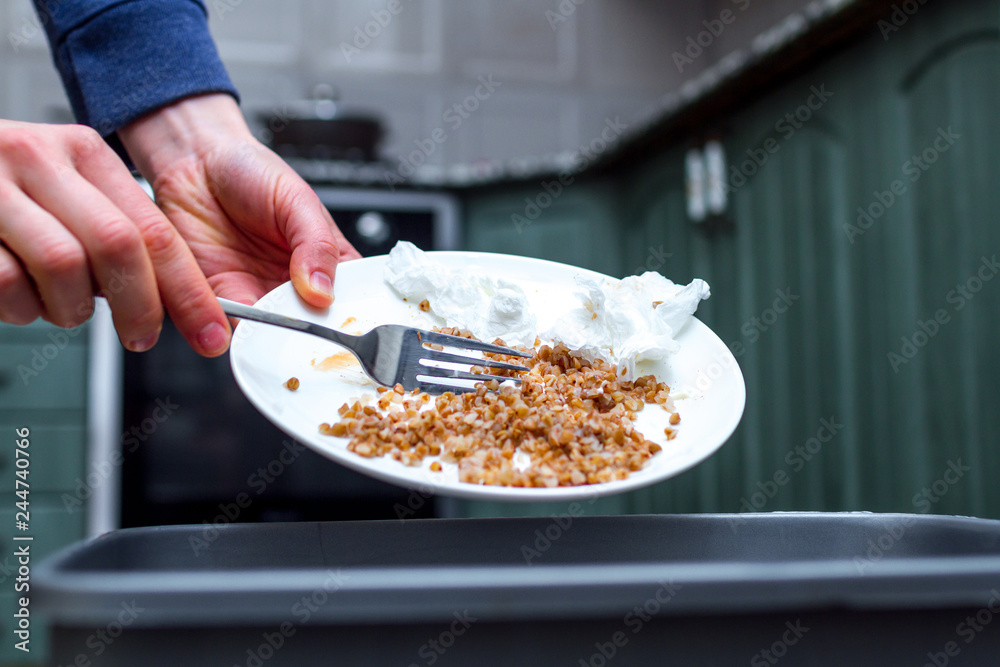 Close up of a person throwing from a plate the leftover of buckwheat to ...