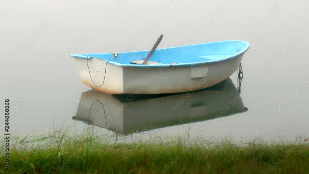 Dinghy rowboat at anchor in a quiet foggy cove with no horizon line ...