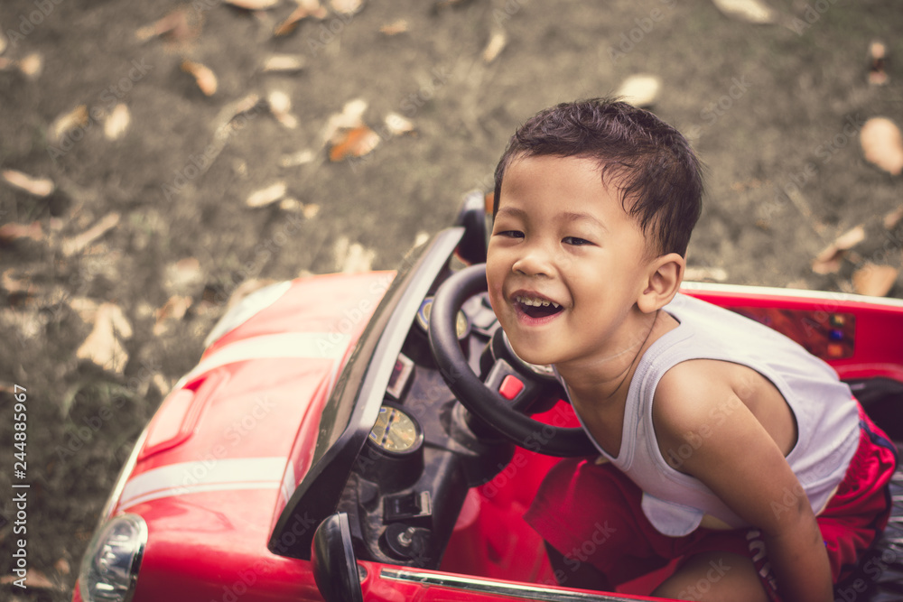 Little boy driving car with the steering wheel. Boy in a white shirt in ...