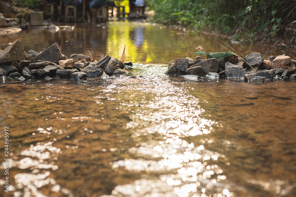 weir in river made from natural stone with people reflection on top ...