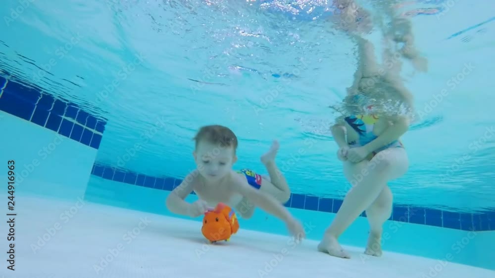Baby takes up a toy from the bottom of the swimming pool vídeo do Stock ...