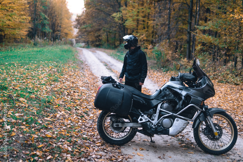 Biker man in leather jacket and black tourist motorcycle with side bags ...