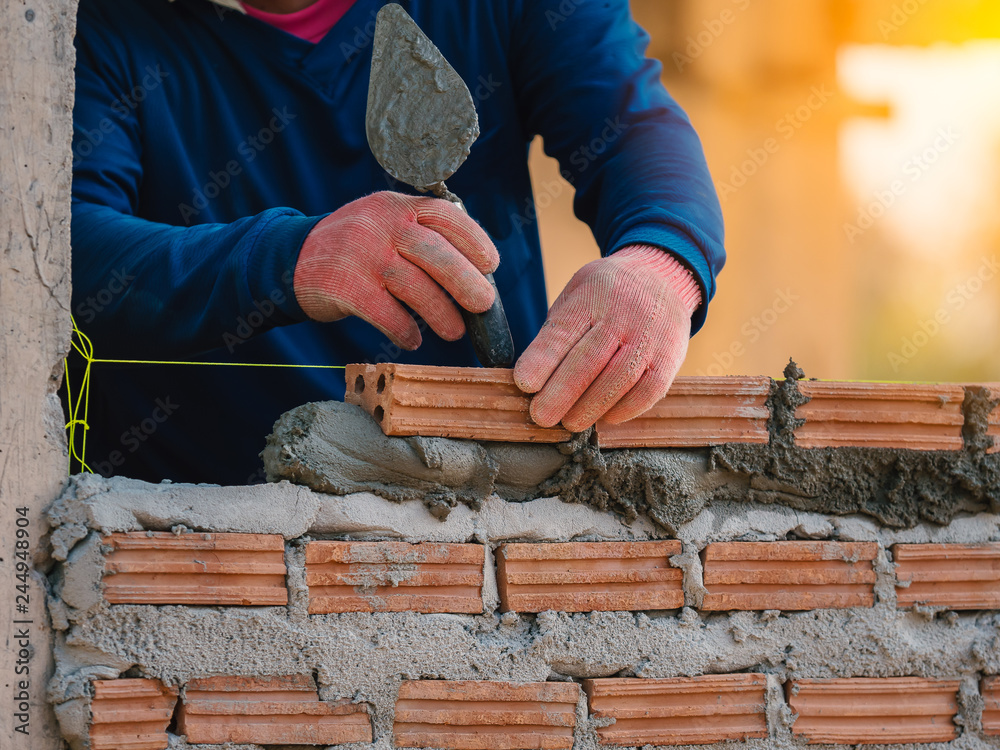 industrial bricklayer worker placing bricks on cement while building ...