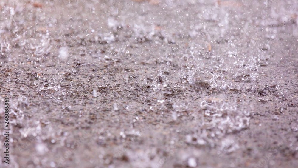 Closeup up view of a rain drops falling on a concrete patio on a ...
