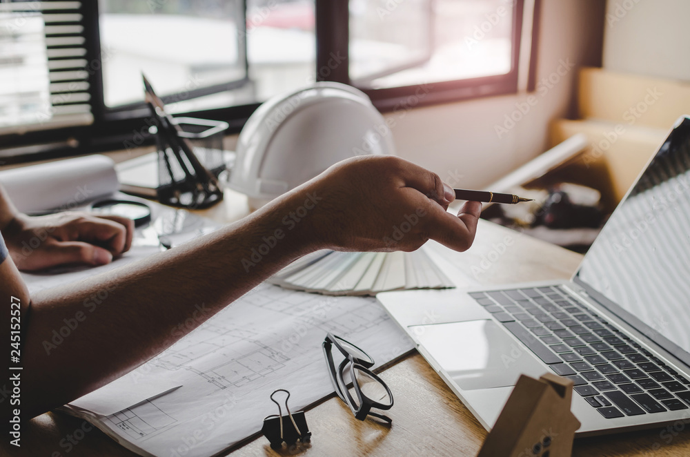 project manager pointing with pen on laptop computer with white safety ...