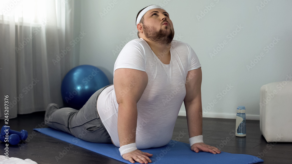 Overweight man stretching home, upward facing dog pose, flexible spine ...